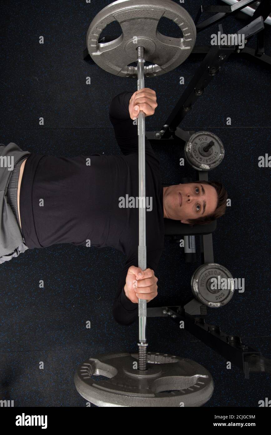 Top view of a fit young male doing a barbell bench press at the gym ...