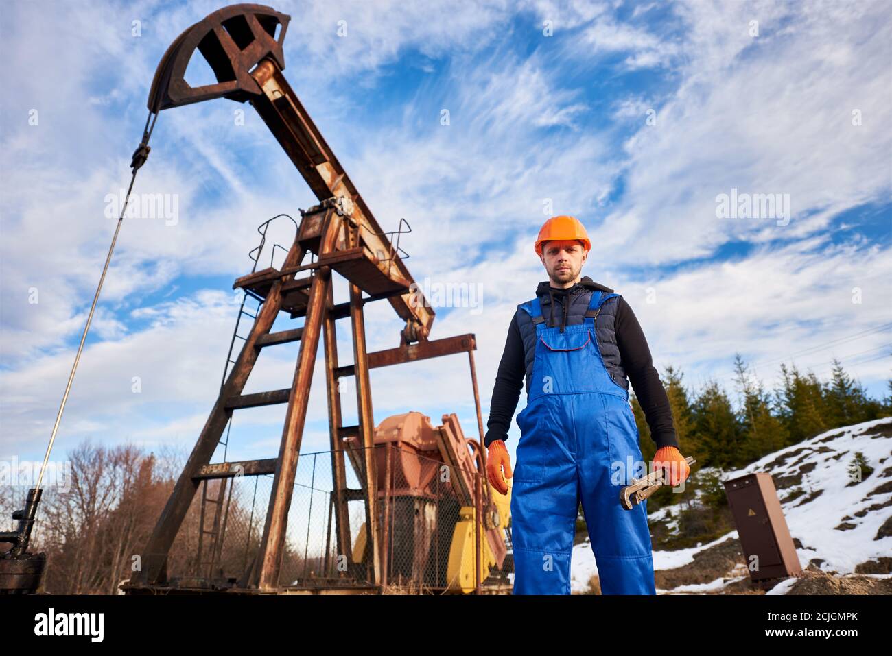 Portrait of oil well enginner in protective helmet and work overalls ...