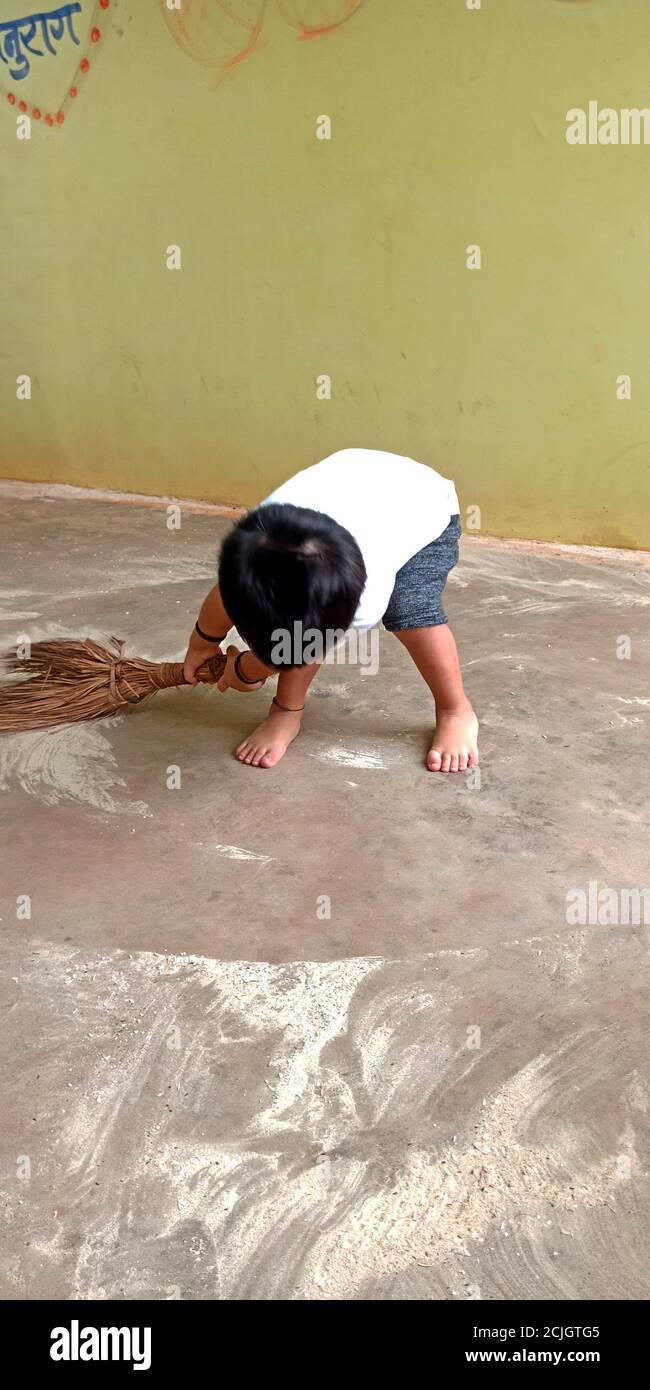 DISTRICT KATNI, INDIA - AUGUST 04, 2019: An indian little boy sweeping ...