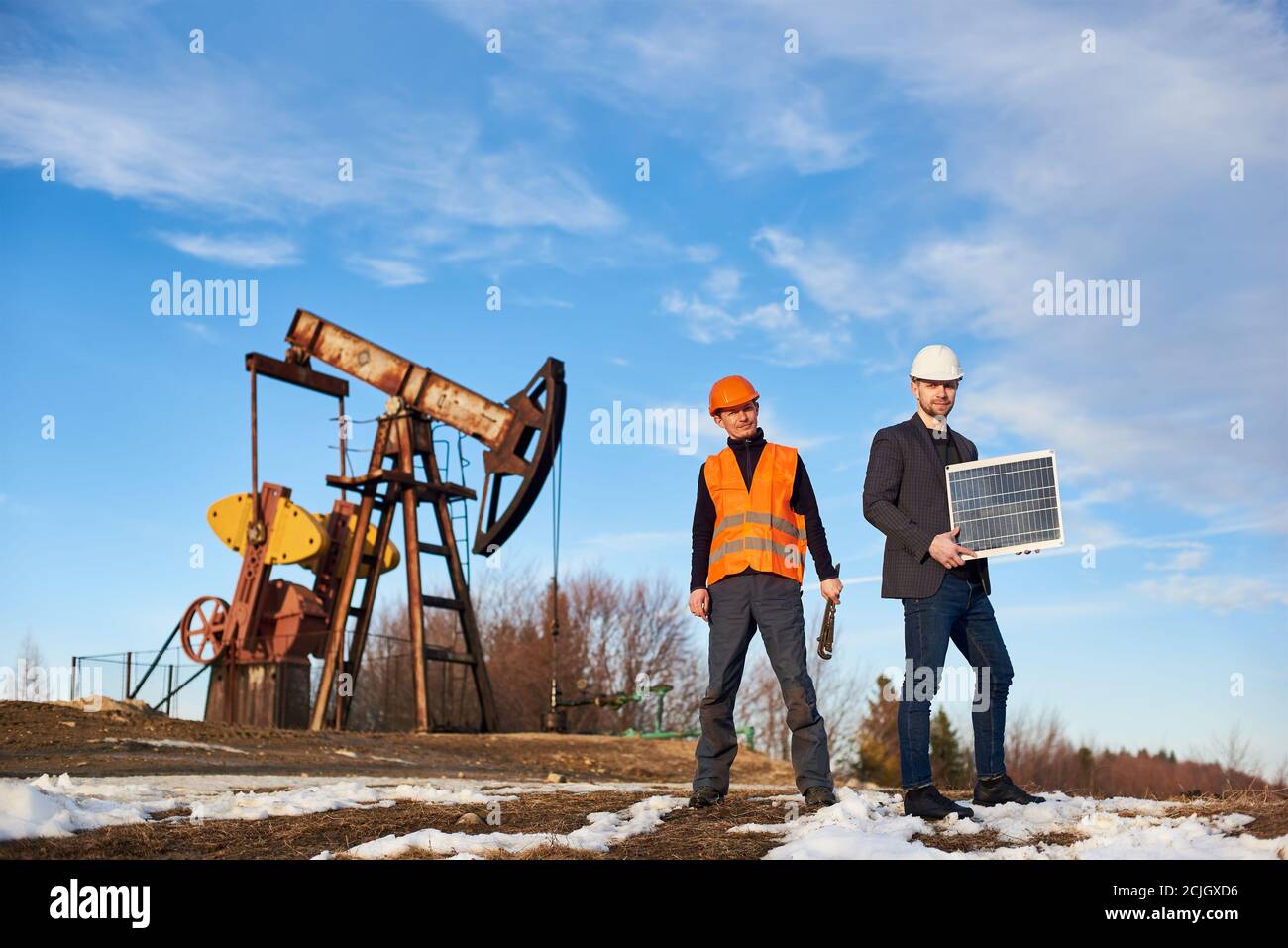 Two men on oil field with pump jack on background. Businessman holding ...