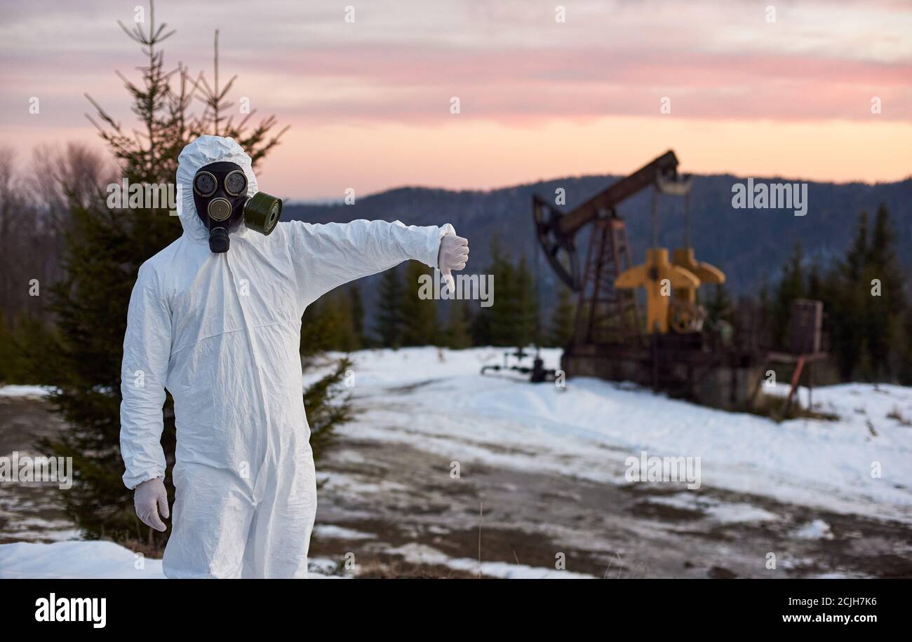 Researcher wearing white coverall, gloves and a gas mask standing in ...