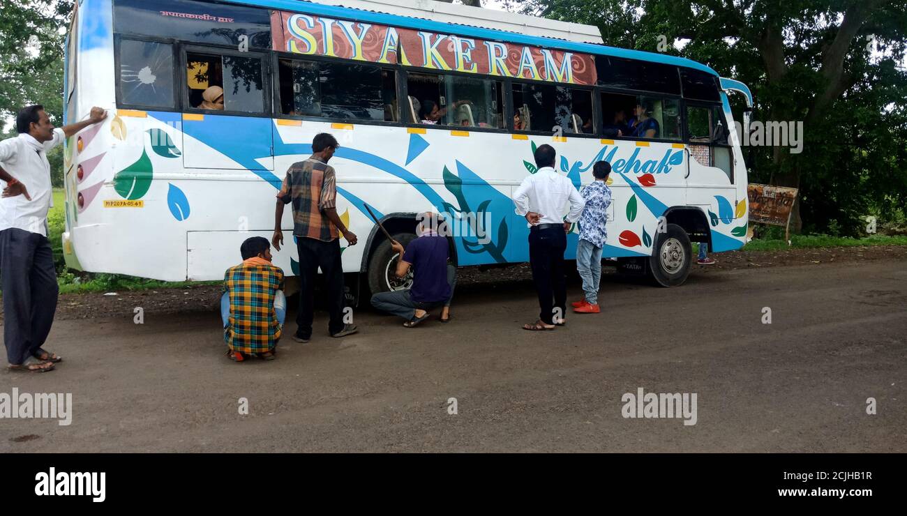 DISTRICT KATNI, INDIA - AUGUST 17, 2019: Asian bus conductor repairing ...