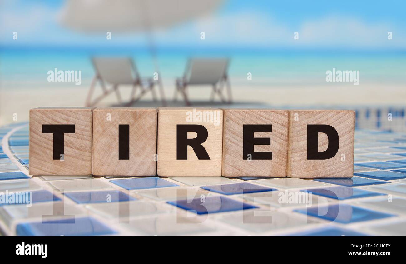 Tired word on wooden cubes on relaxed beach background. Relax vacation ...