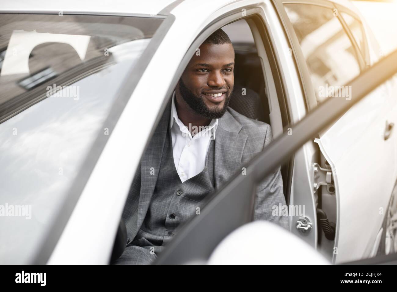 Handsome black businessman in expensive suit getting in car Stock Photo ...