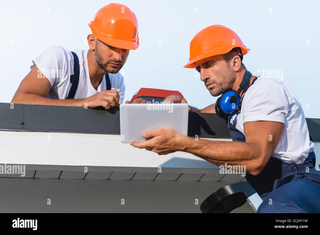 Selective focus of handymen in workwear using digital tablet while ...
