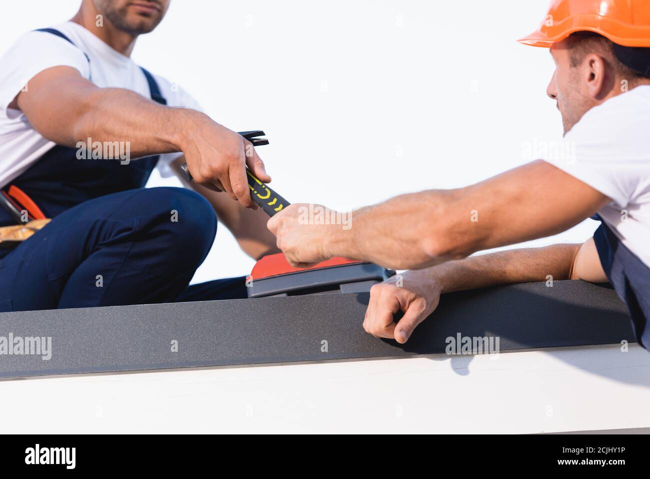 Selective focus of handyman giving hammer to colleague while working on ...