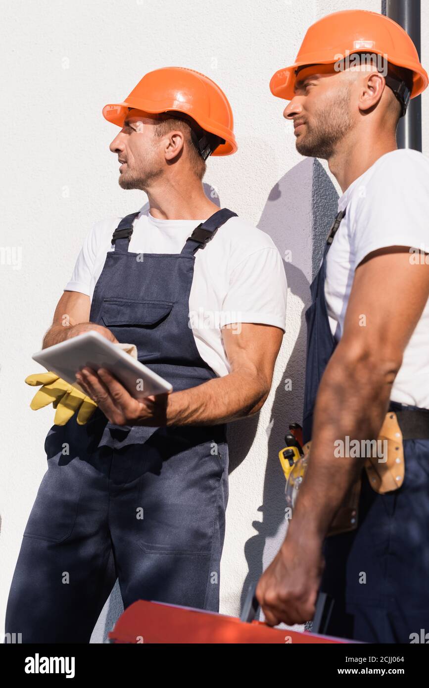 Selective focus of handymen with digital tablet and toolbox standing ...