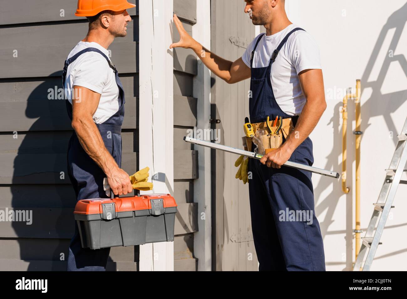 Builders with tools and toolbox standing near facade of building Stock ...