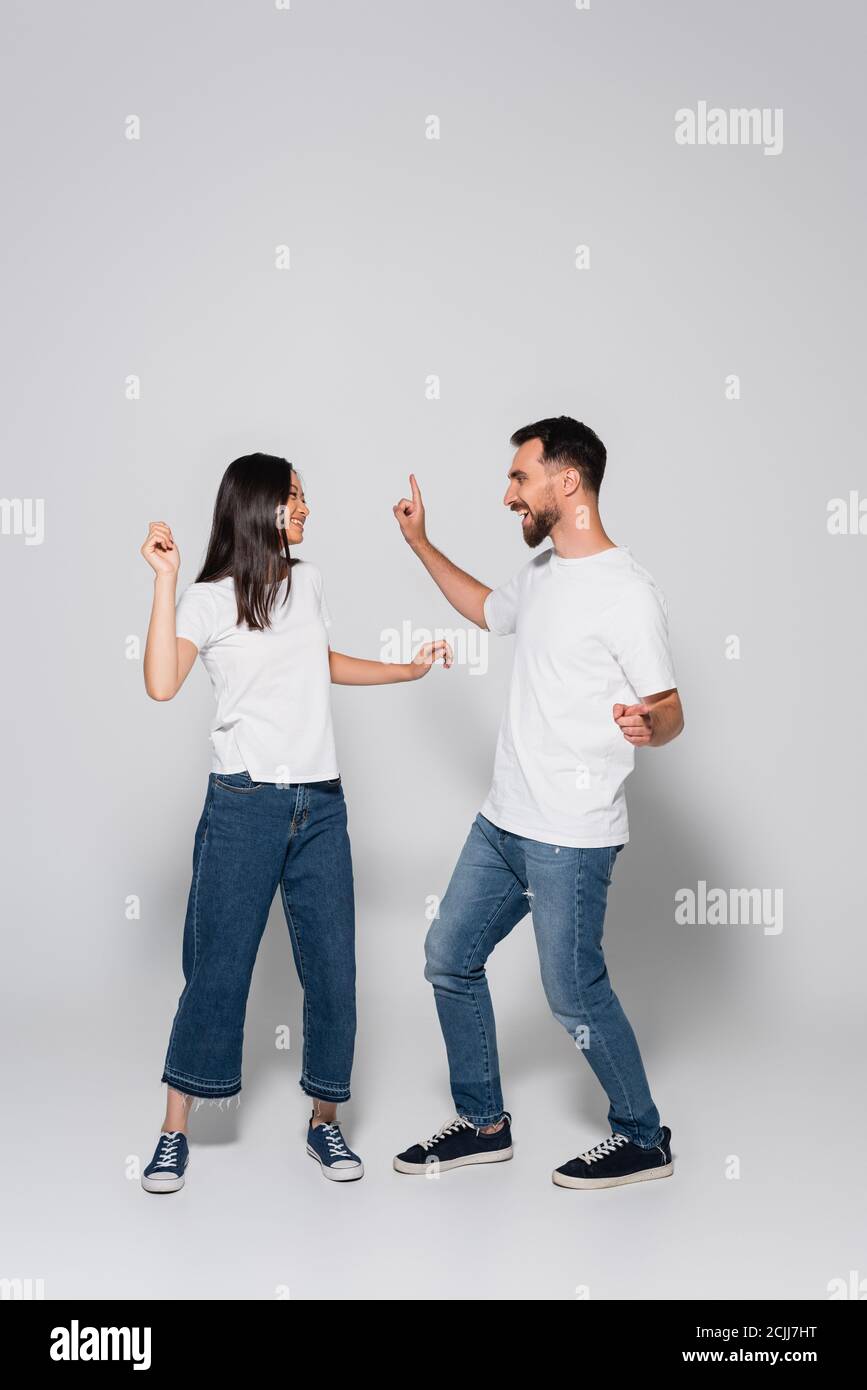 young interracial couple in jeans, white t-shirts and gumshoes dancing ...