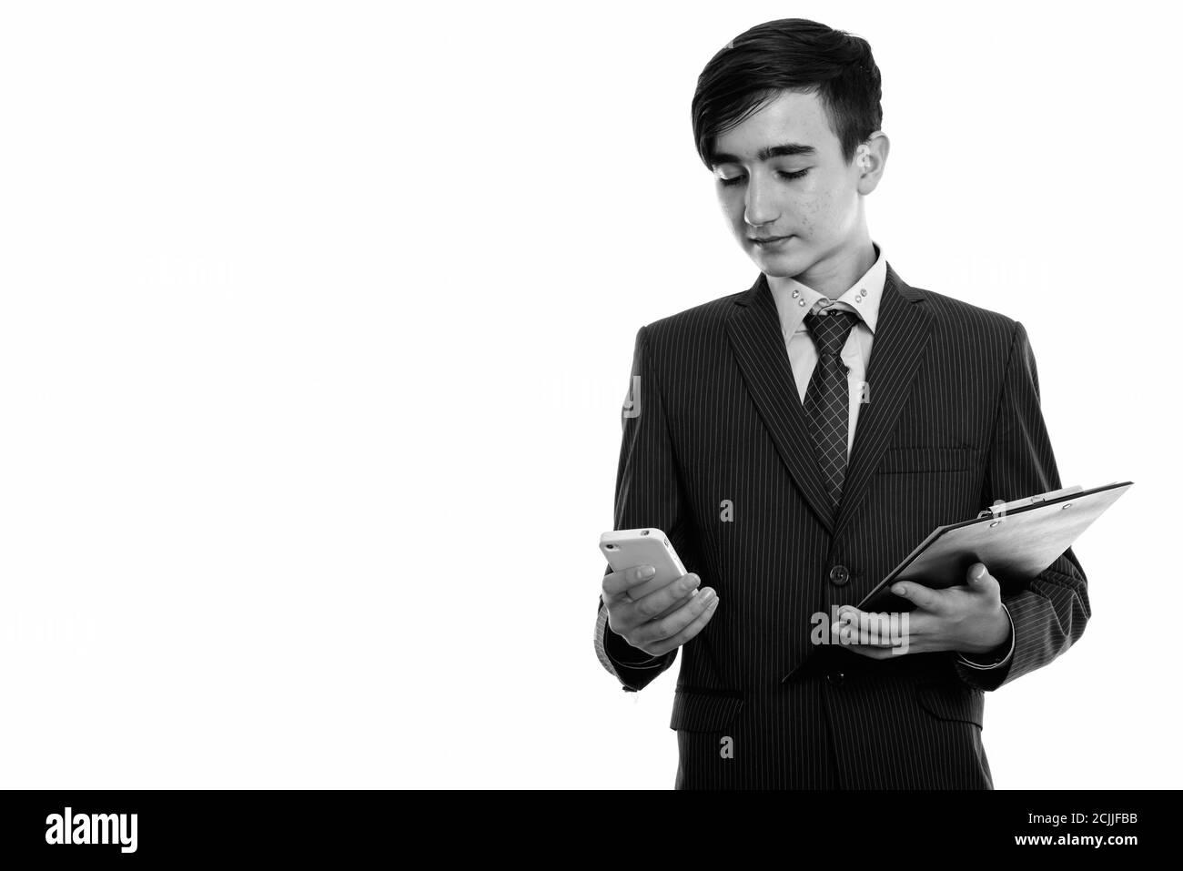 Studio shot of young handsome Persian teenage businessman using mobile ... Studio shot of young handsome Persian teenage businessman using mobile ...