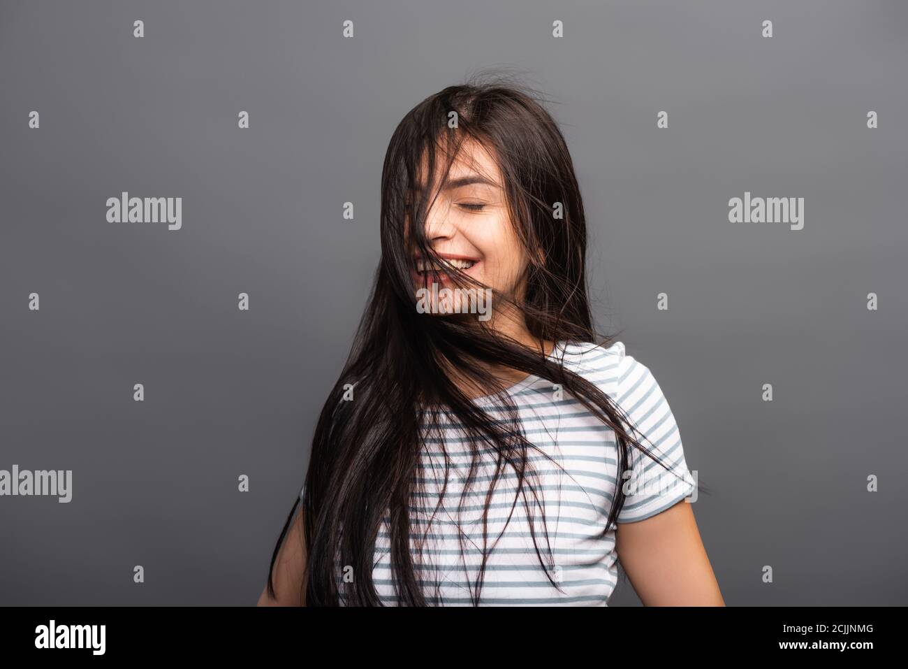wind blowing through hair of brunette woman with closed eyes isolated ...