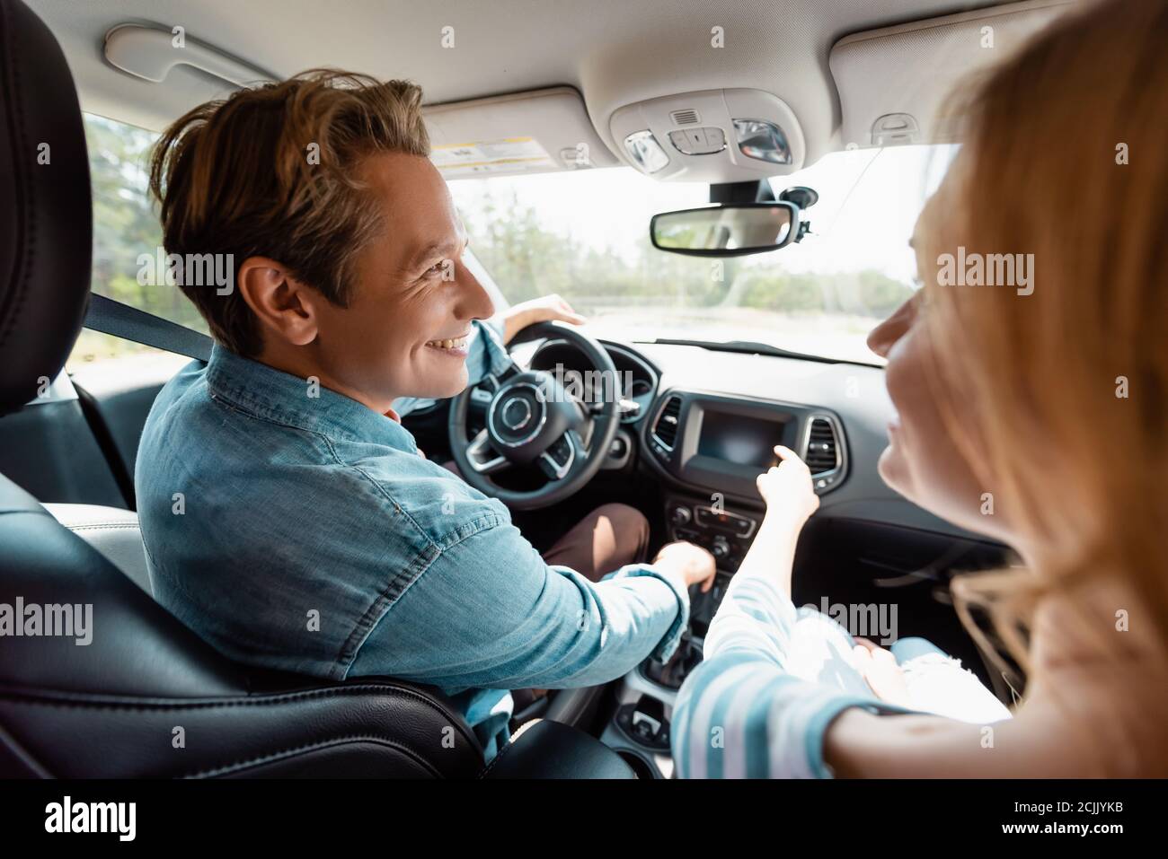 Selective focus of woman pointing with finger near husband driving car ...