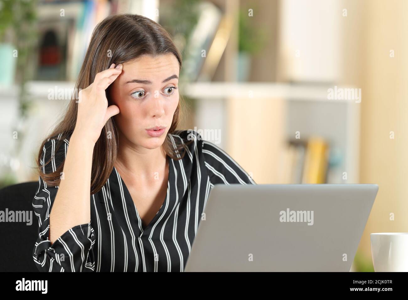 Worried woman discovering error on laptop sitting at home Stock Photo ...