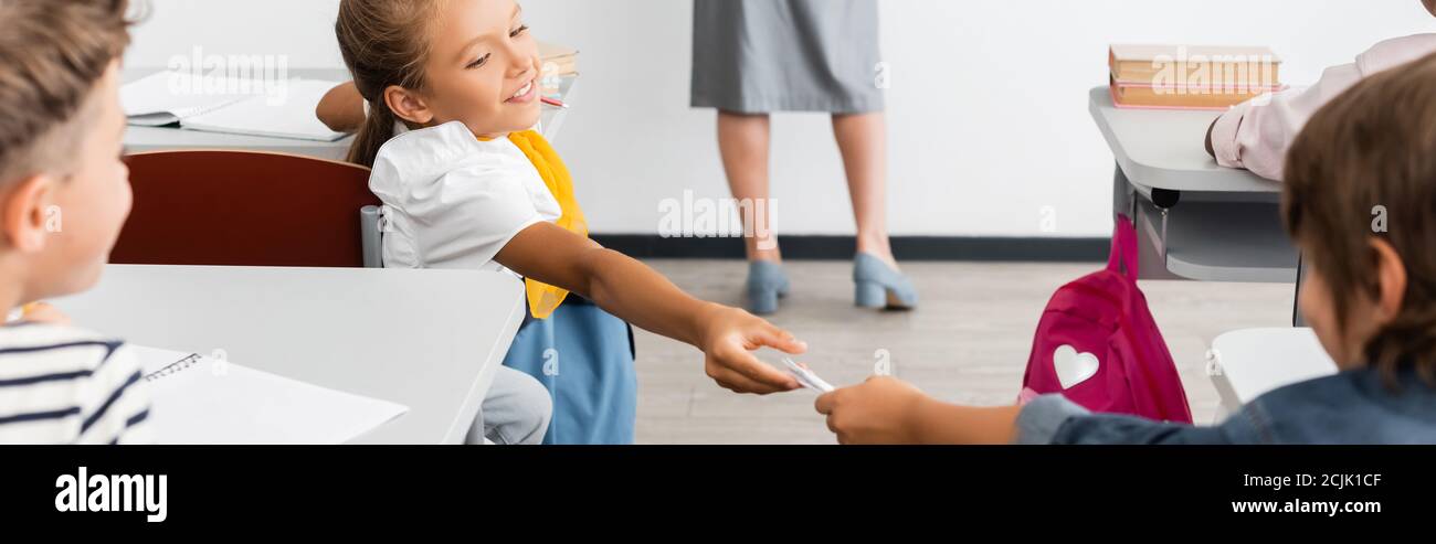 selective focus of schoolgirl taking note from classmate during lesson ...