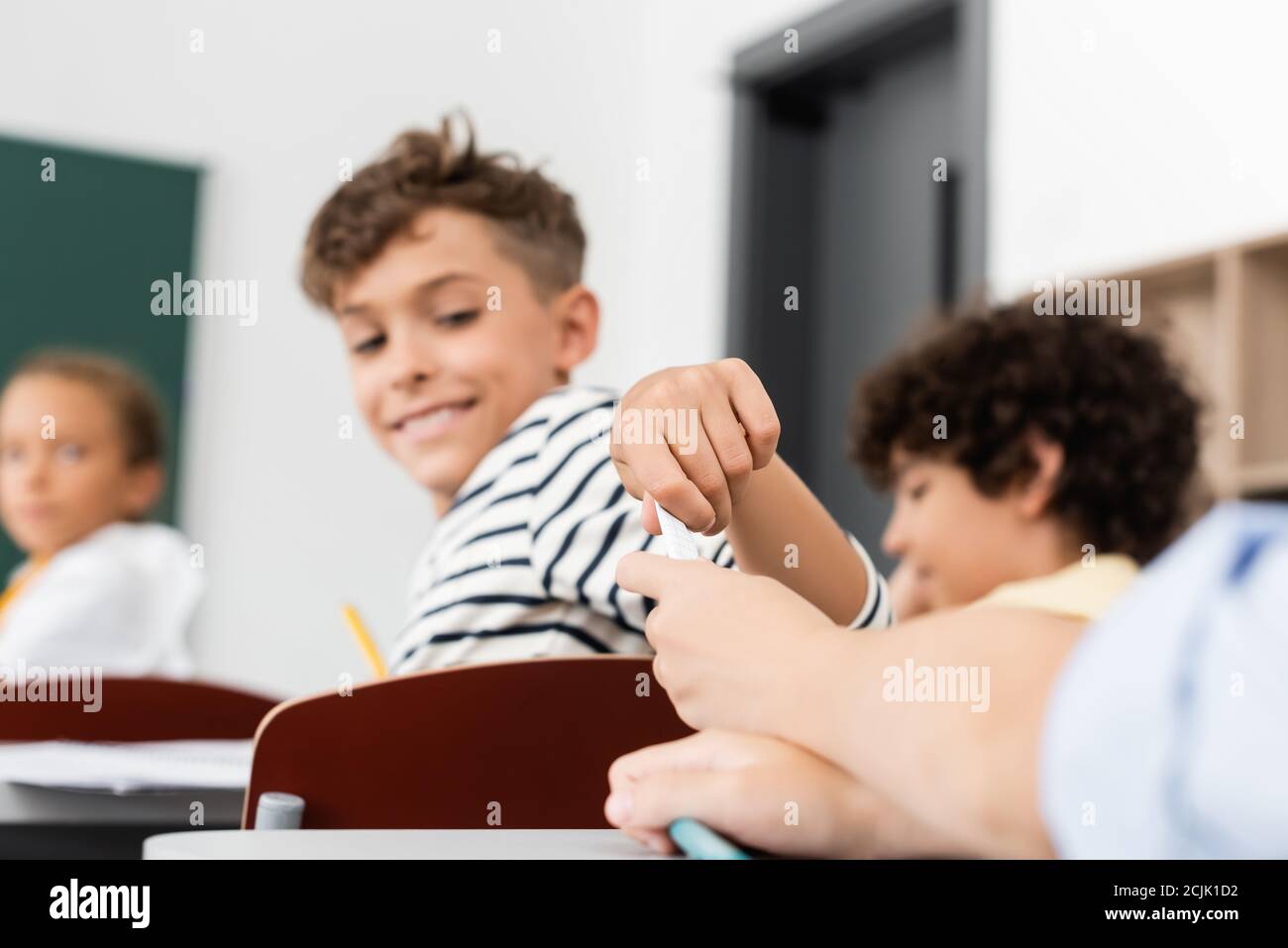 cropped view of schoolkid passing note to classmate near multicultural ...