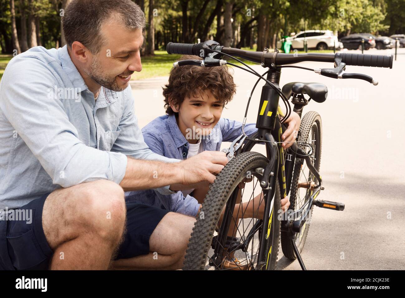 Closeup portrait of cheerful dad and son fixing bike Stock Photo - Alamy