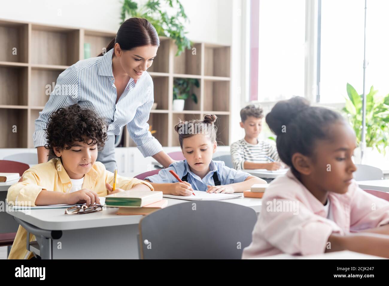 Selective focus of teacher standing near multiethnic pupils during ...