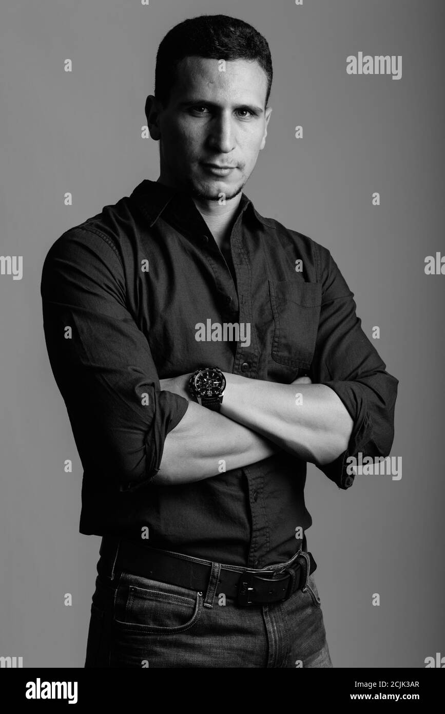 Studio shot of young muscular Persian man with arms crossed against ...