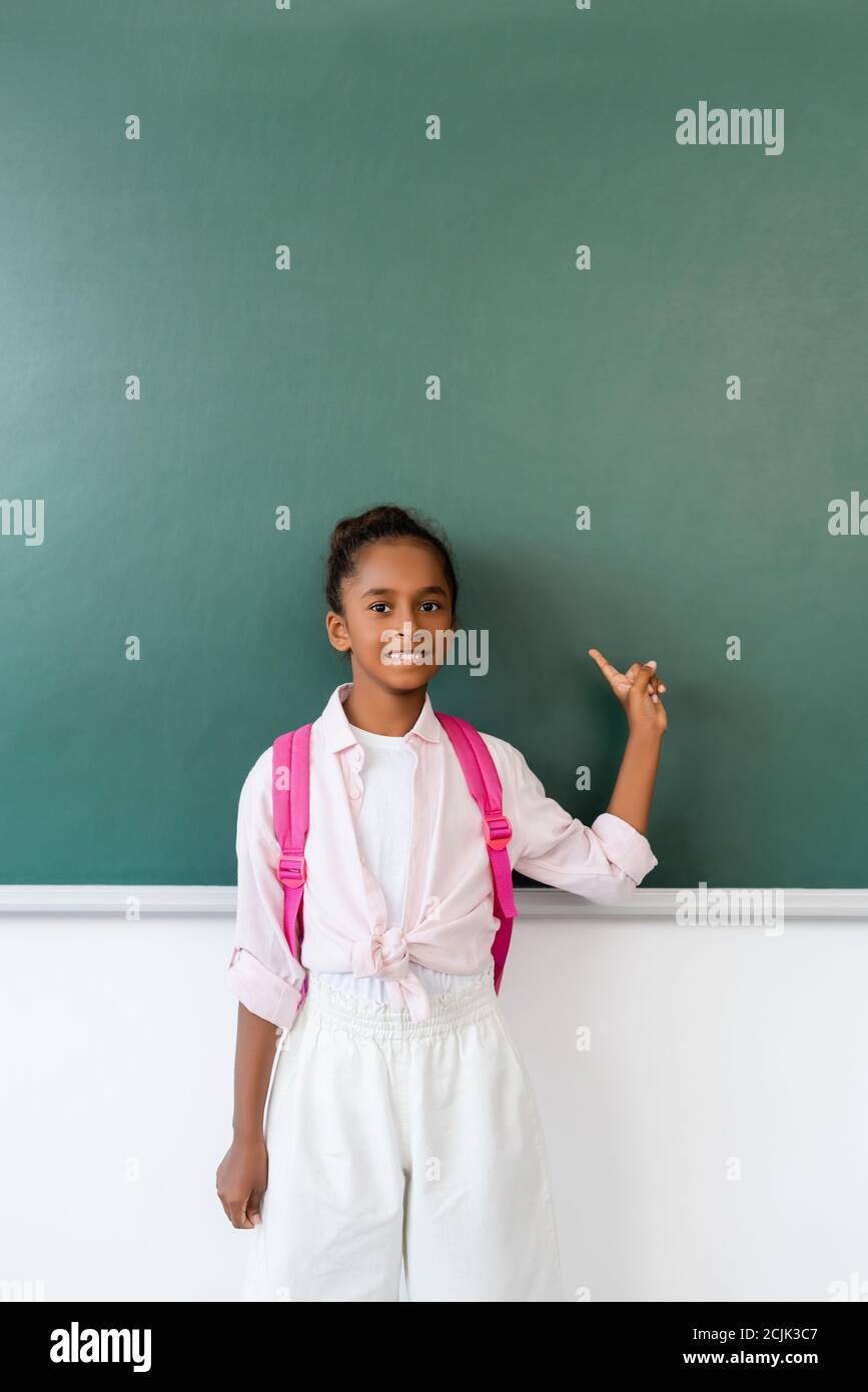African american schoolgirl pointing with finger at chalkboard in ...