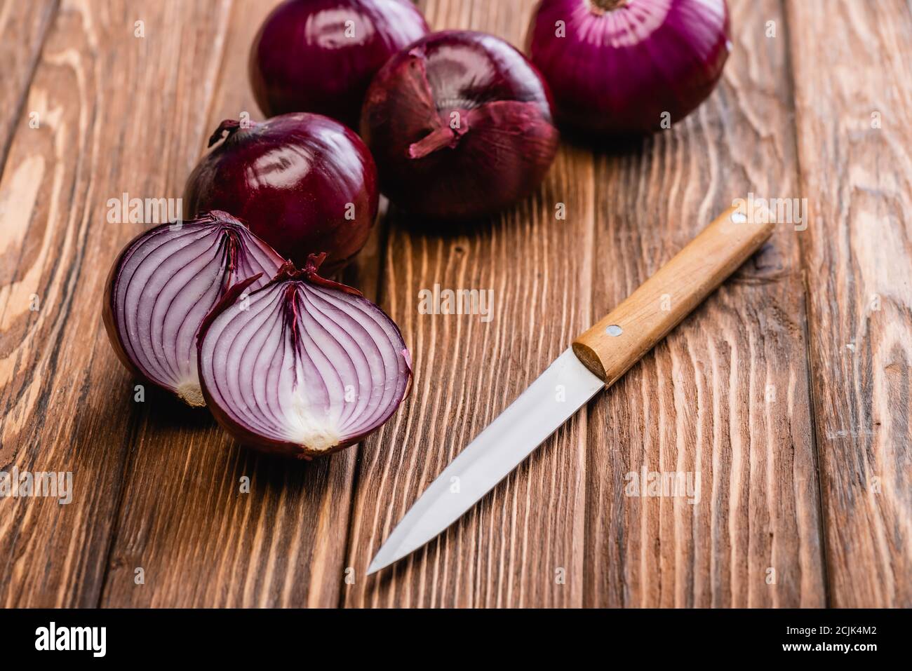 cut and whole red onion near knife on wooden table Stock Photo - Alamy