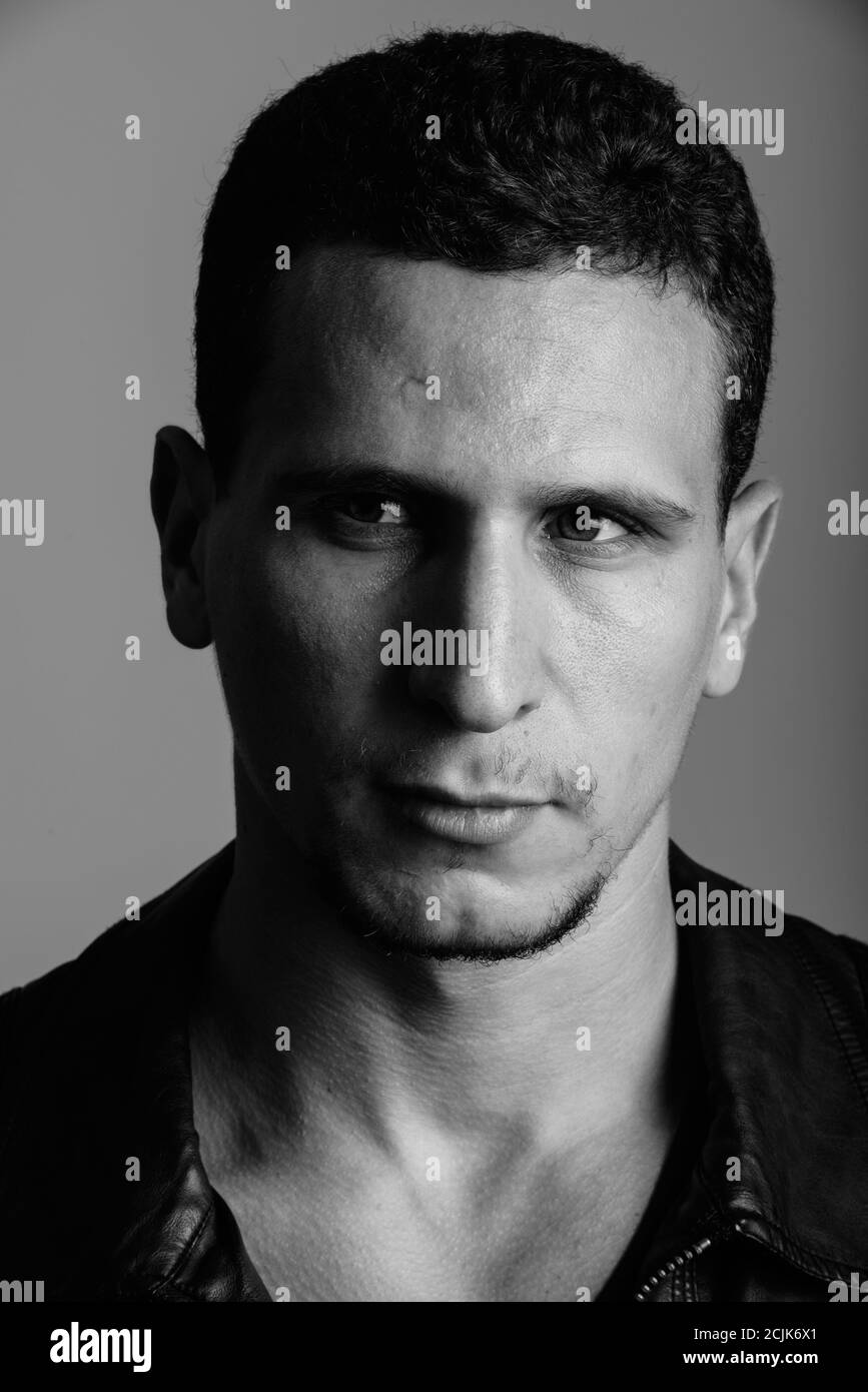 Face of young muscular Persian man thinking while looking at distance ...