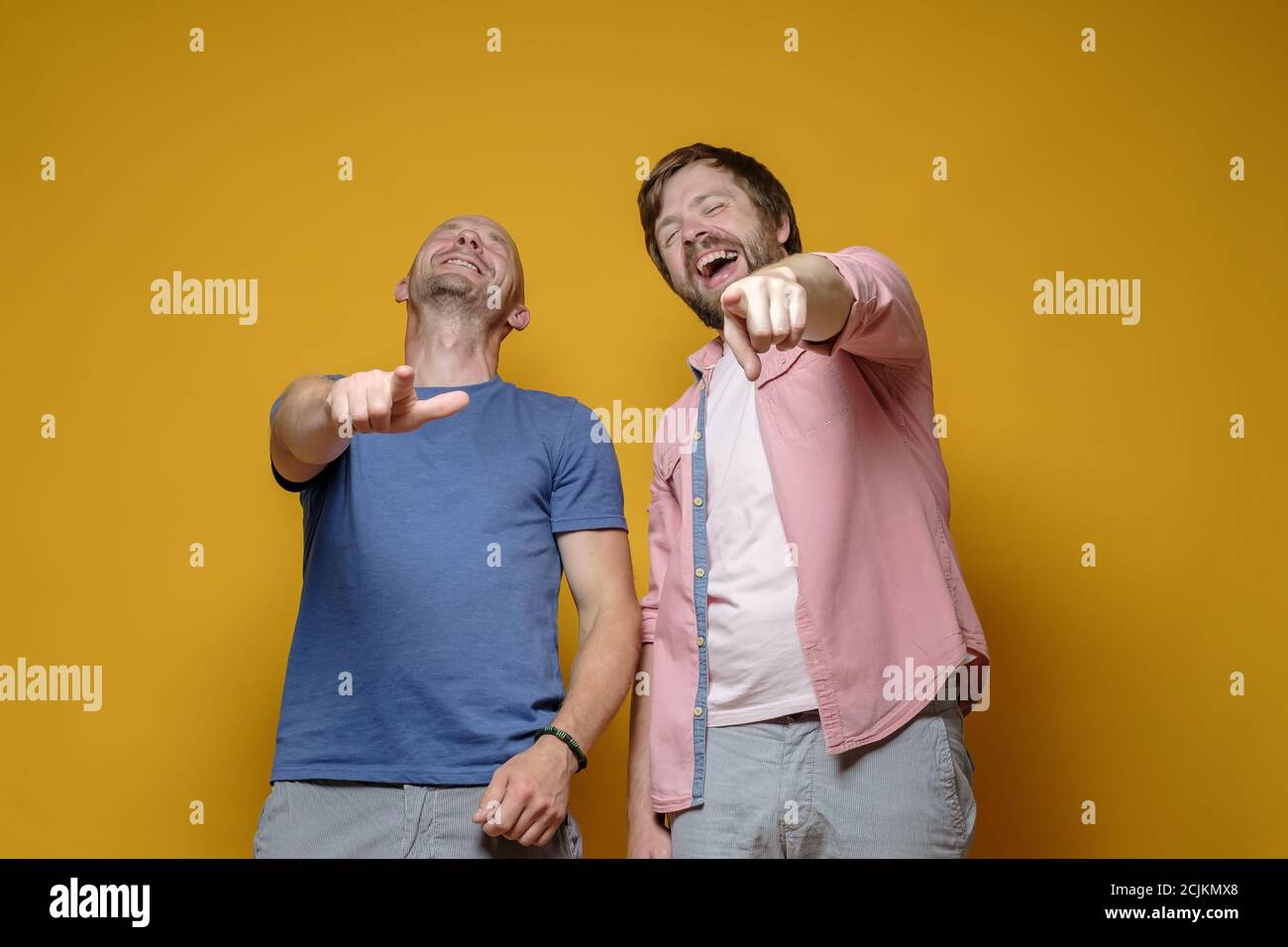 Two Caucasian men in casual clothes laugh mercilessly at someone and ...