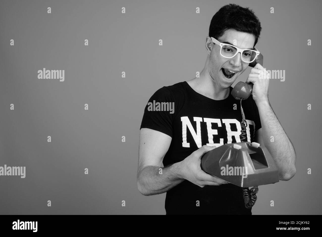 Portrait of happy young Persian nerd man with old telephone Stock Photo - Alamy