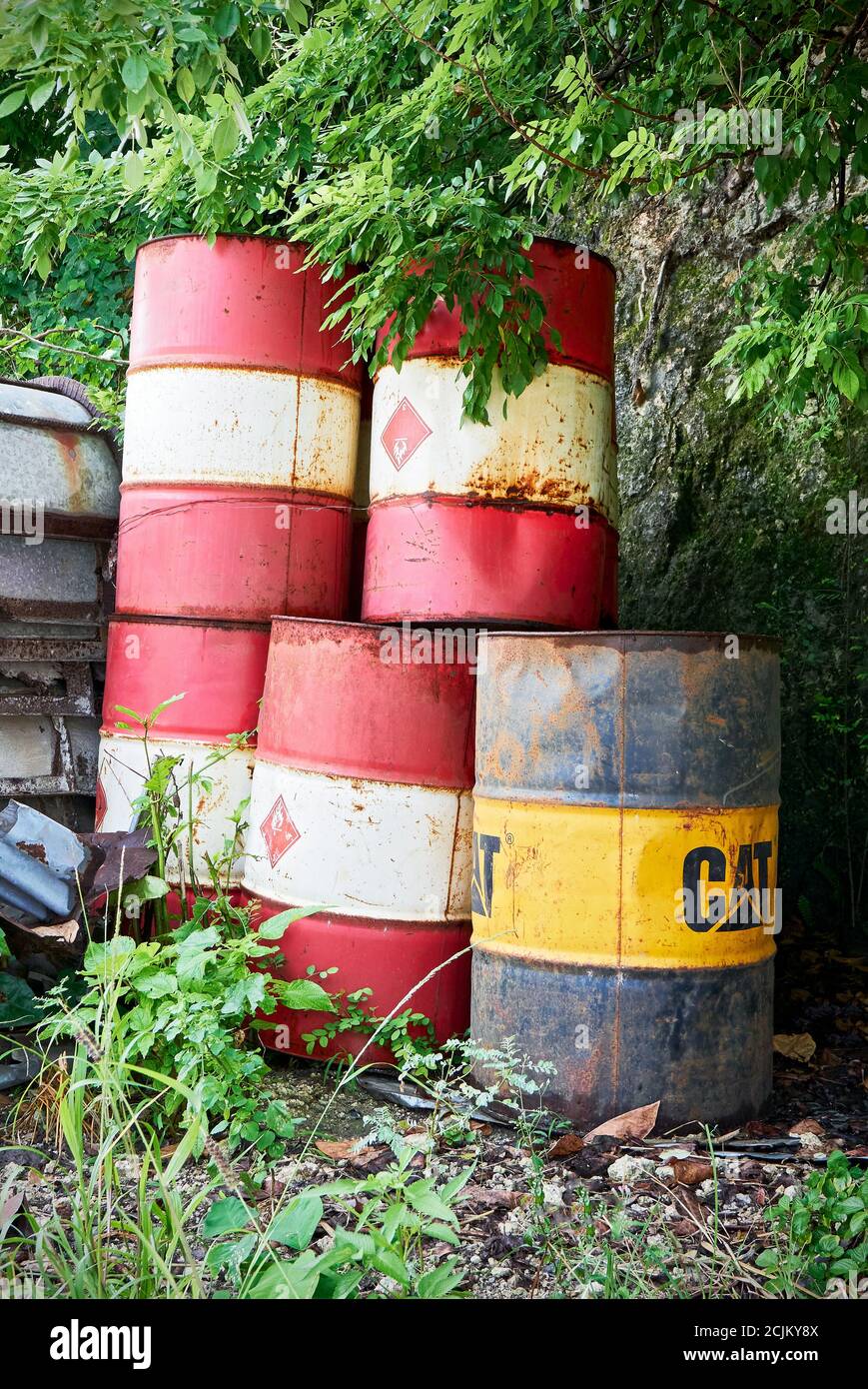 Many old, rusty drums piled up next to metal road construction ...