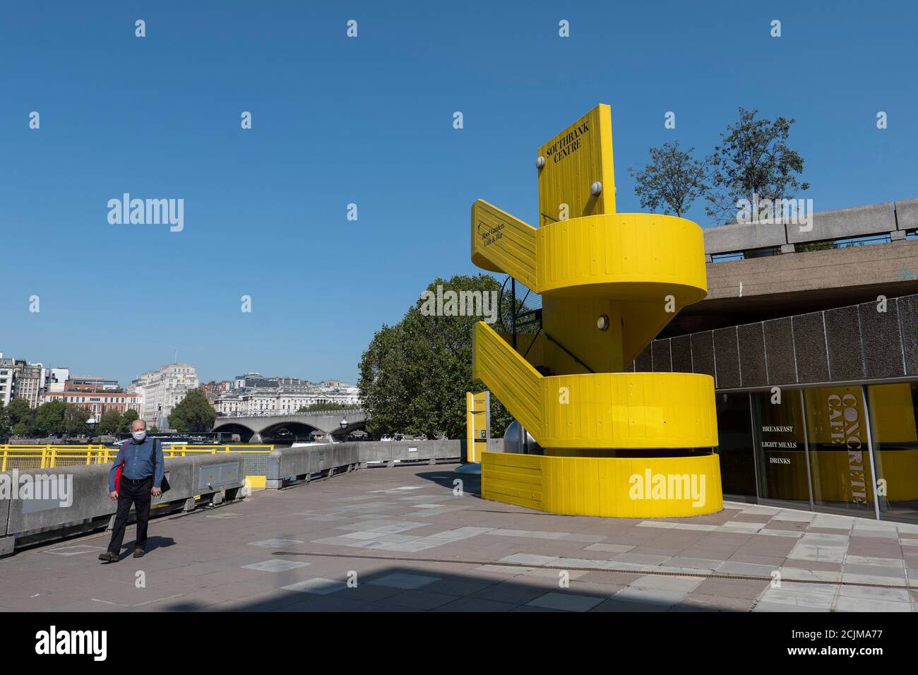 London, England. A man wearing a blue face mask walks past the iconic ...