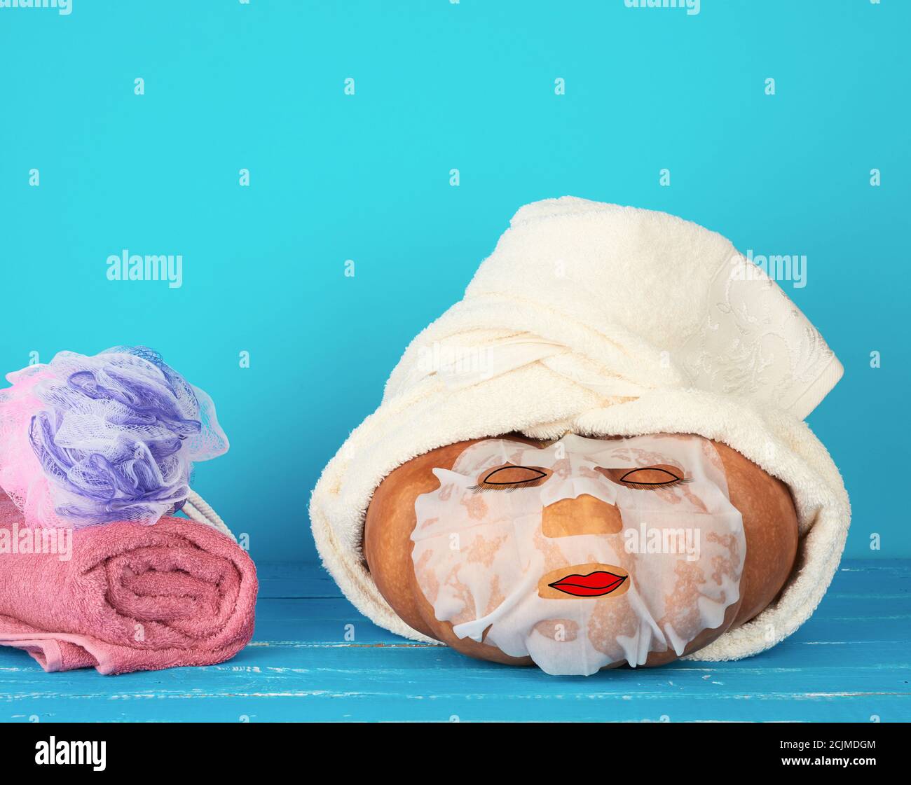 round orange pumpkin wrapped in a white terry towel, face mask on the ...