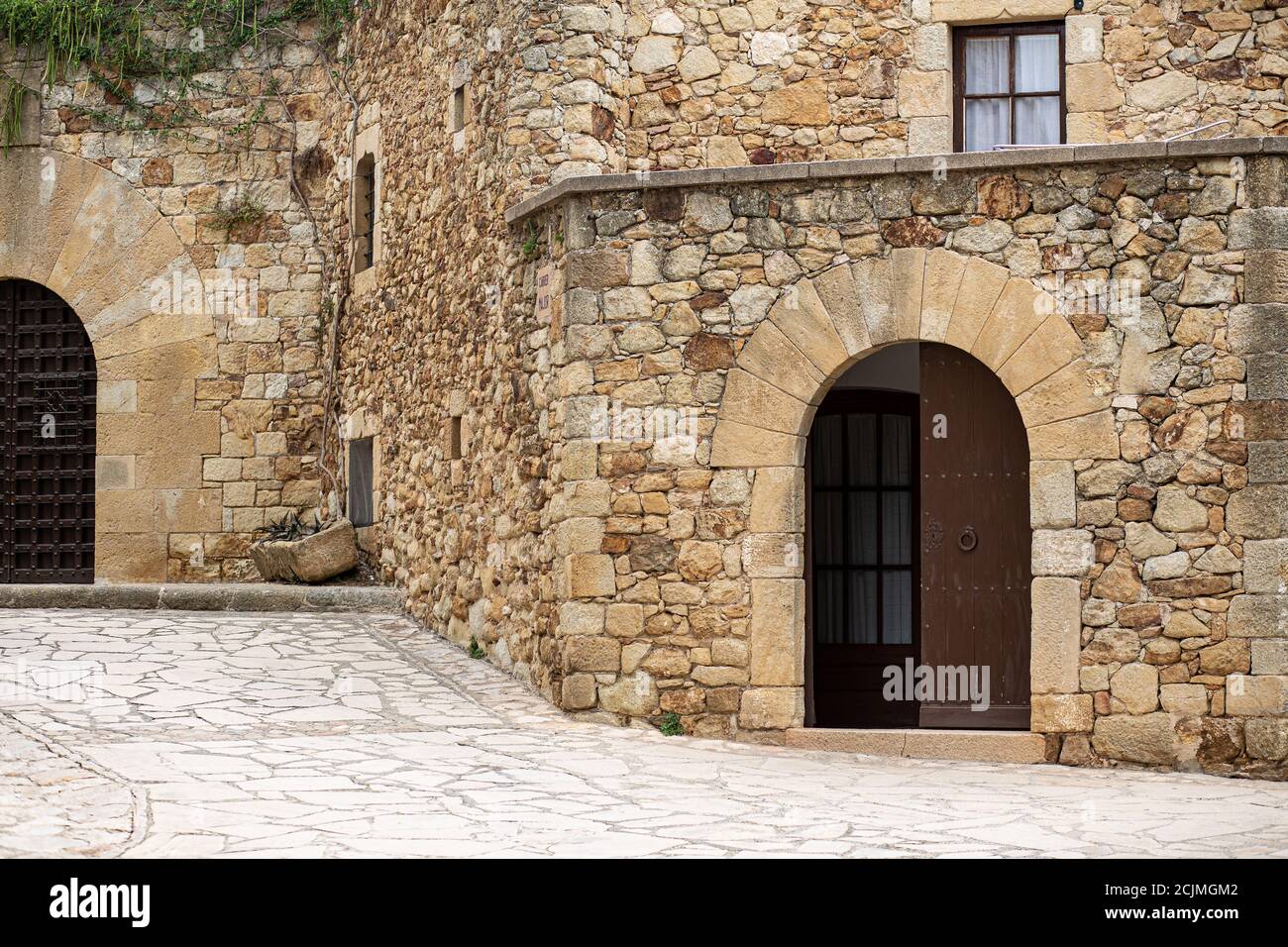Old rock and stone medieval restored house with an arc door on a cobble ...