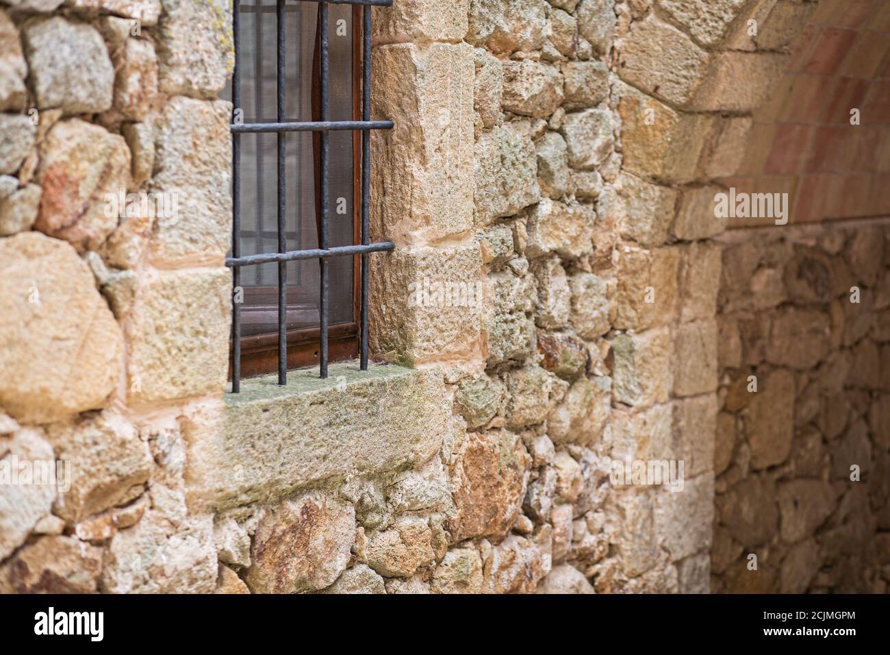 Old closed window protected with metal fence on an old rock stone wall ...