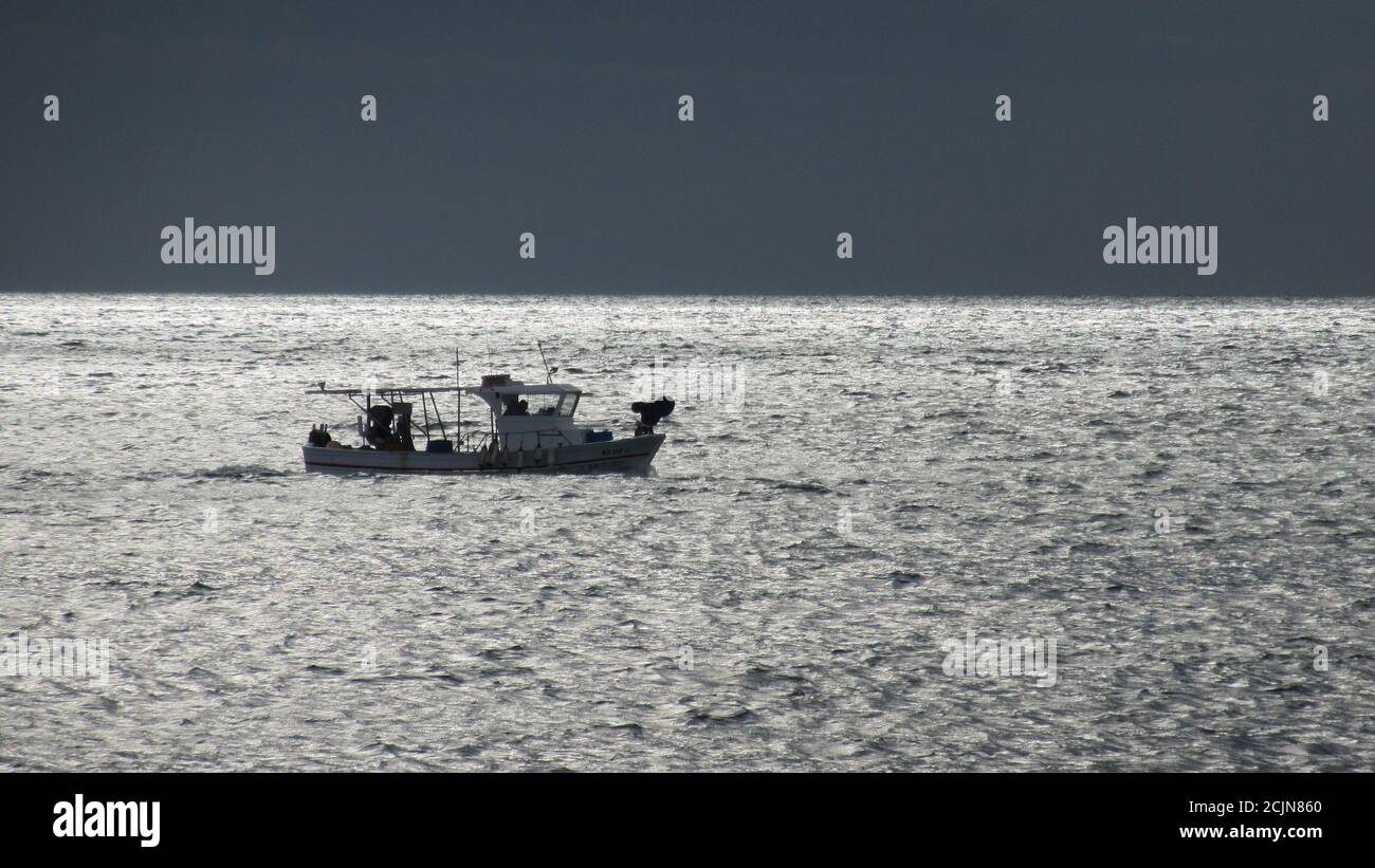 Fishing bout out in sea at sunset Stock Photo - Alamy