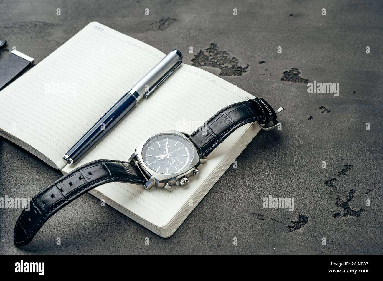 Male watch and notepad on dark grey table Stock Photo - Alamy