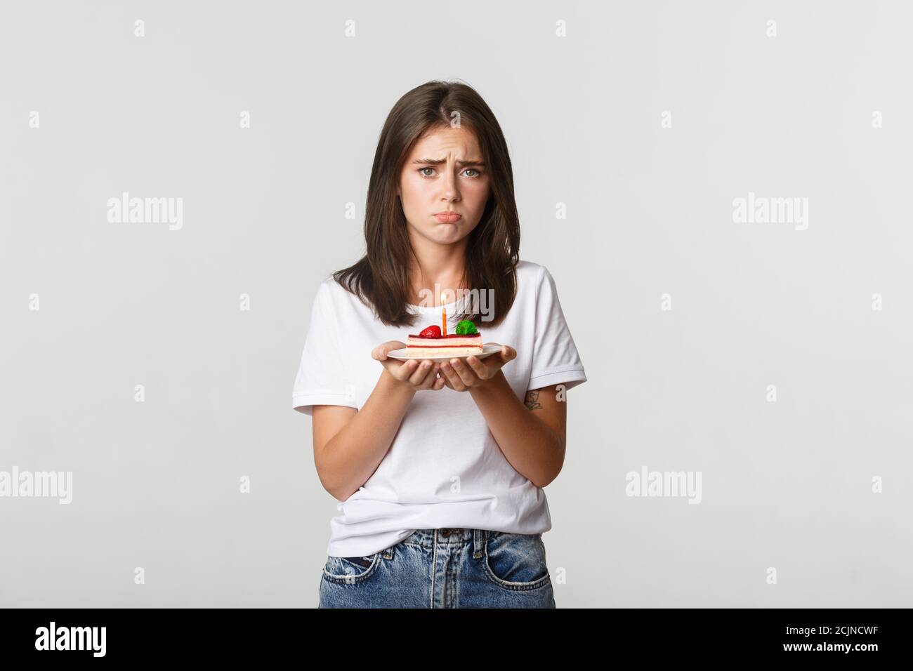 Miserable birthday girl looking sad, holding b-day cake with candle ...