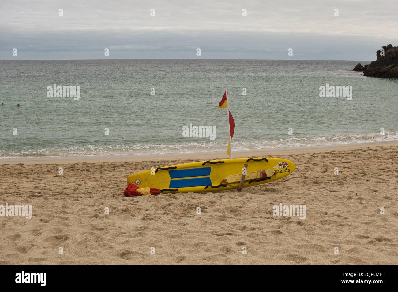 Lifeguard's RNLI surfboard and flags on the beach at Porthcurno ...