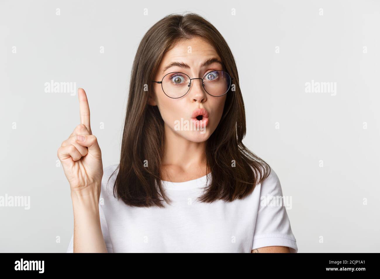 Close-up of smart cute girl in glasses raising finger eureka gesture ...