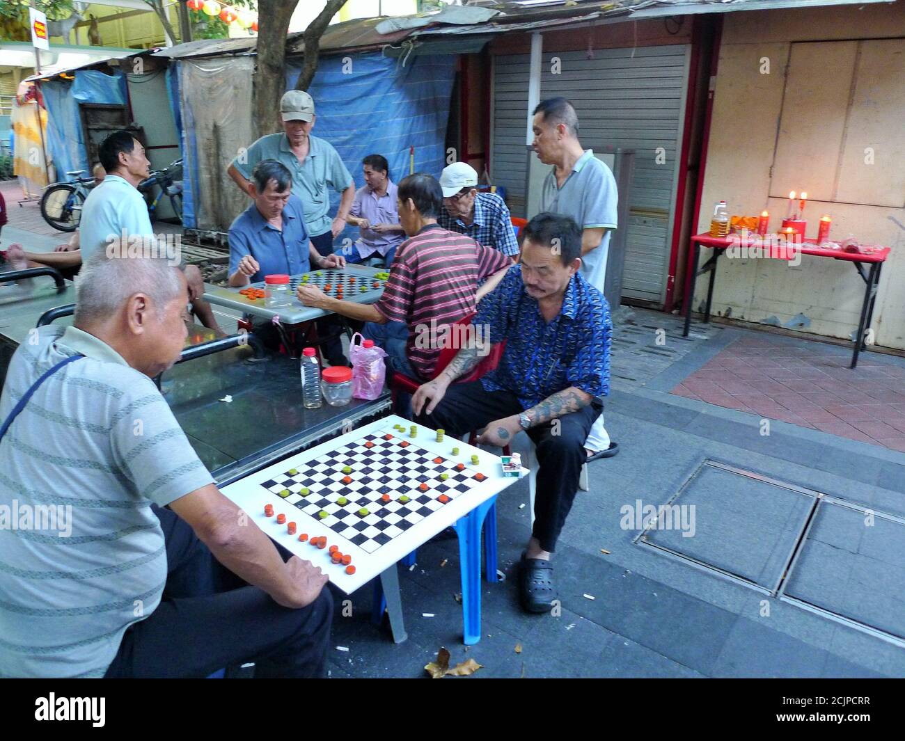MEN FROM THE CHINESE COMMUNITY SITTING INSIDE CHINATOWN ON A SUMMER ...