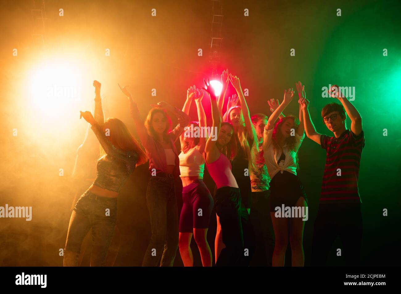 Shadows. A crowd of people in silhouette raises their hands, dancing on ...