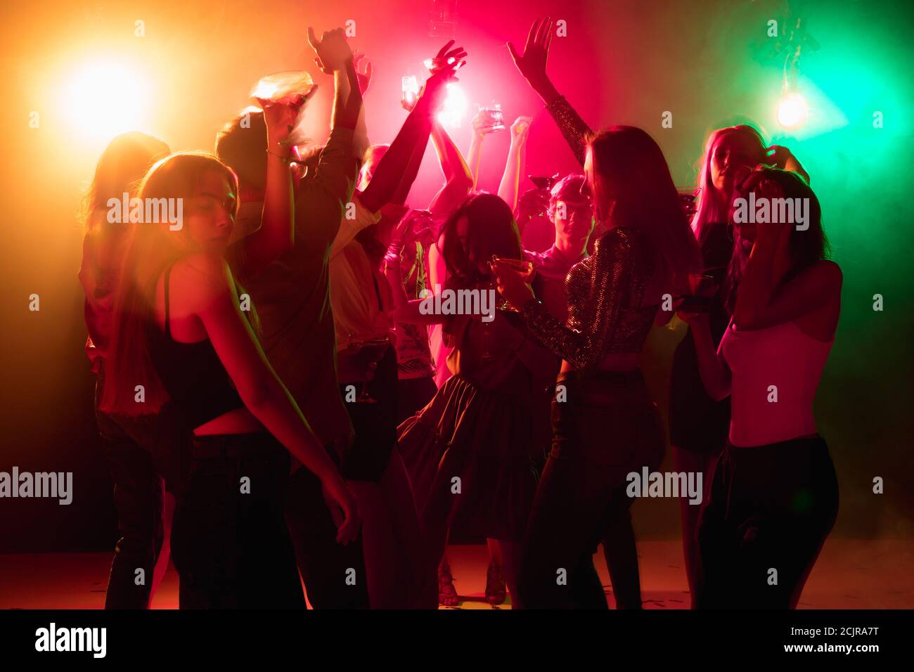 Energy. A crowd of people in silhouette raises their hands, dancing on ...