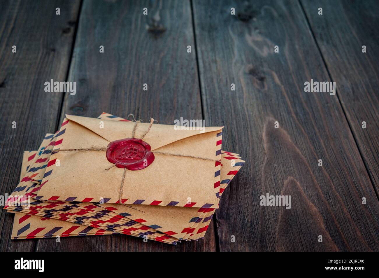 Old letters envelopes with a wax magic stamp triquetra on wooden table ...
