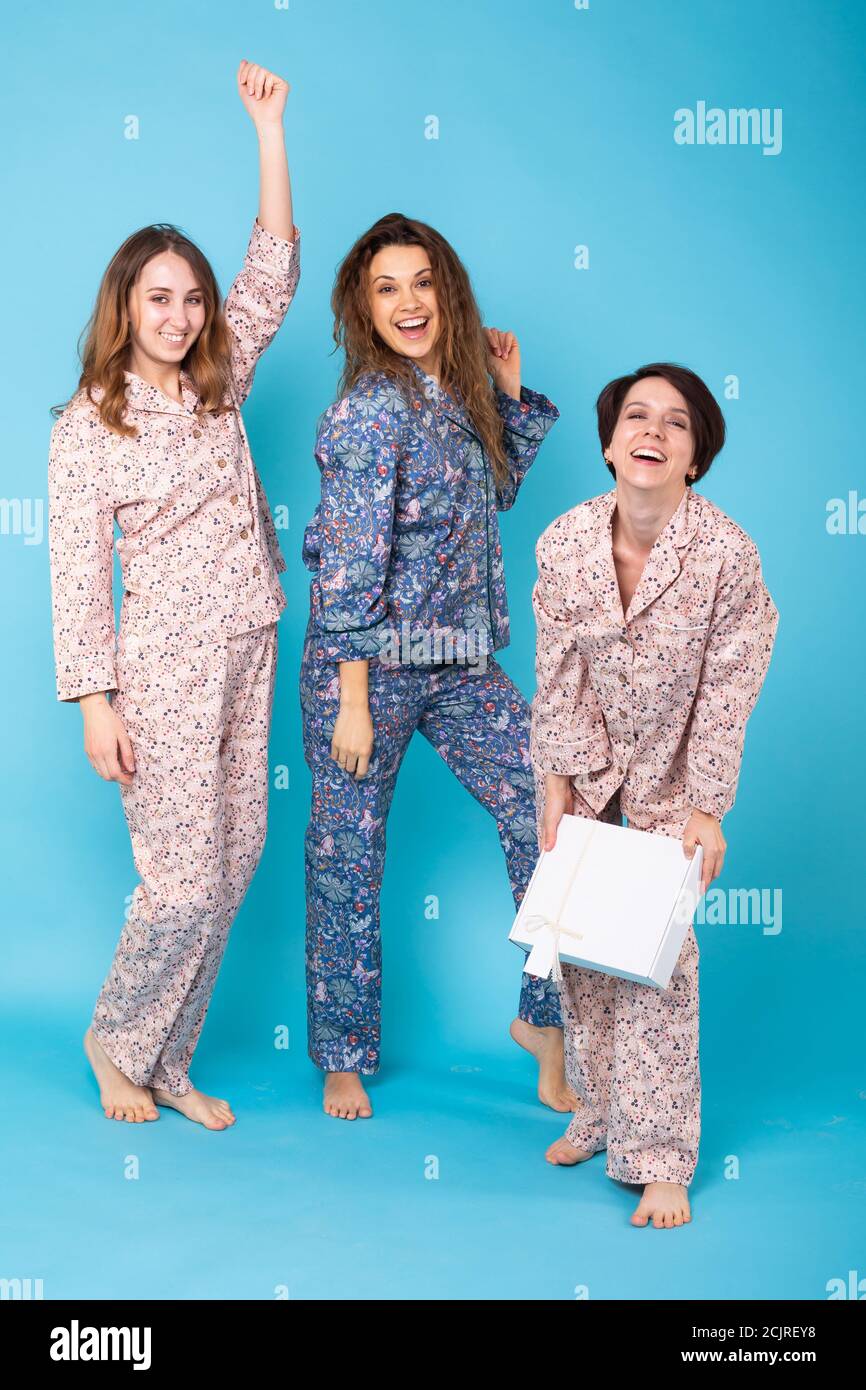 Portrait of three beautiful young girls wearing colorful pyjamas having ...