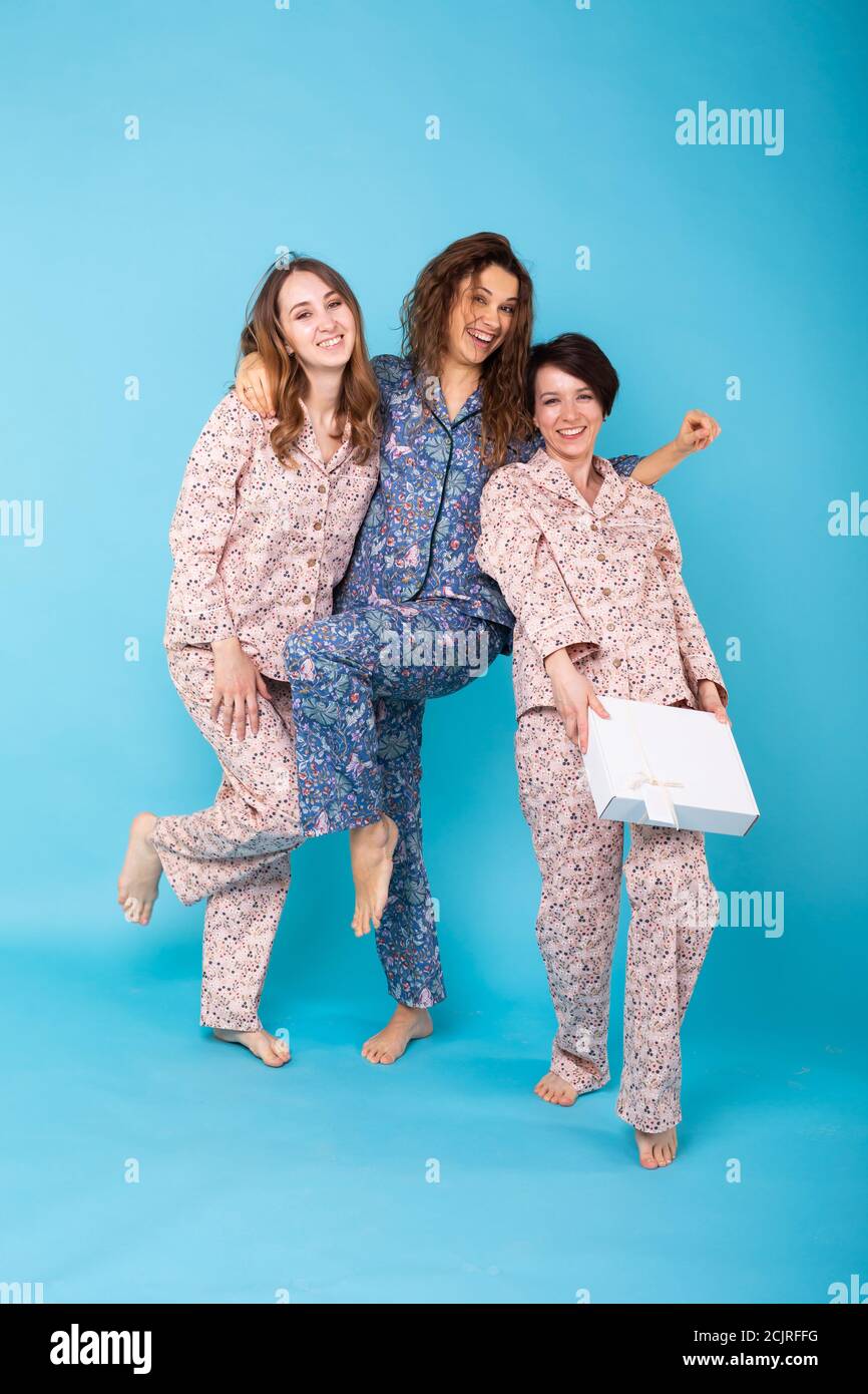 Portrait of three beautiful young girls wearing colorful pyjamas having ...