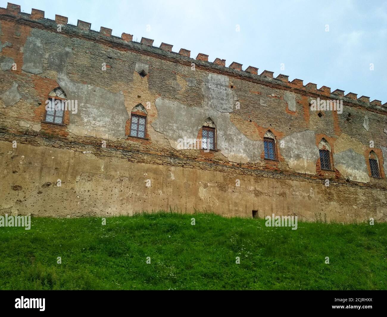 defensive wall of the old castle with an earthen rampart and grass at ...