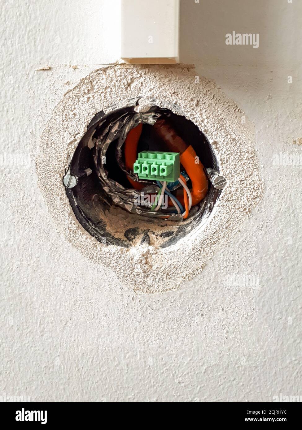 Vertical closeup shot of a hole in the wall with electrical wirings ...