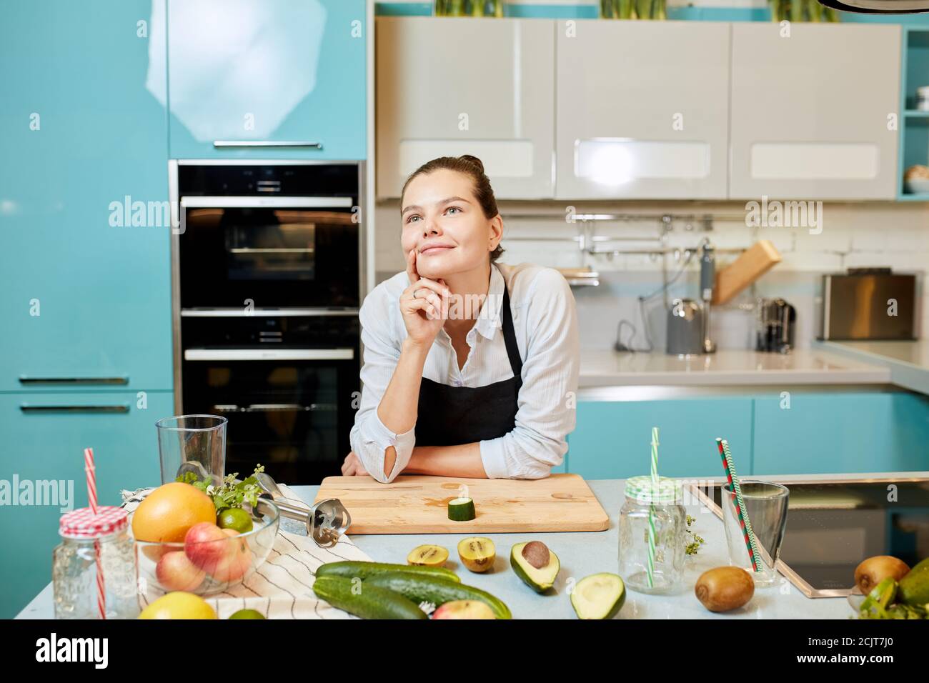 cheerful gorgeous girl making up a new recipe of dish in the kitchen ...