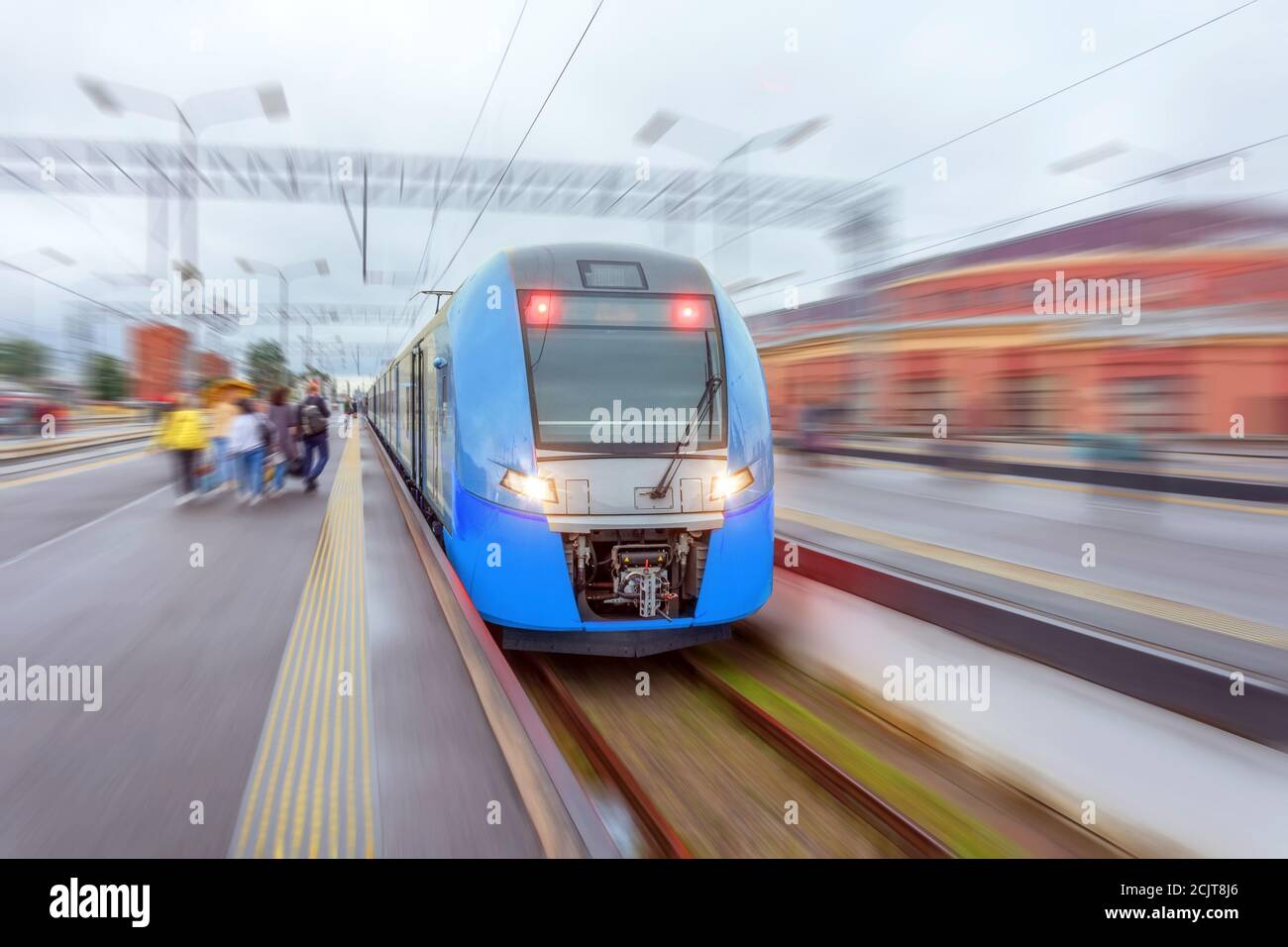 High speed suburban train passes by the passenger station at fast ...