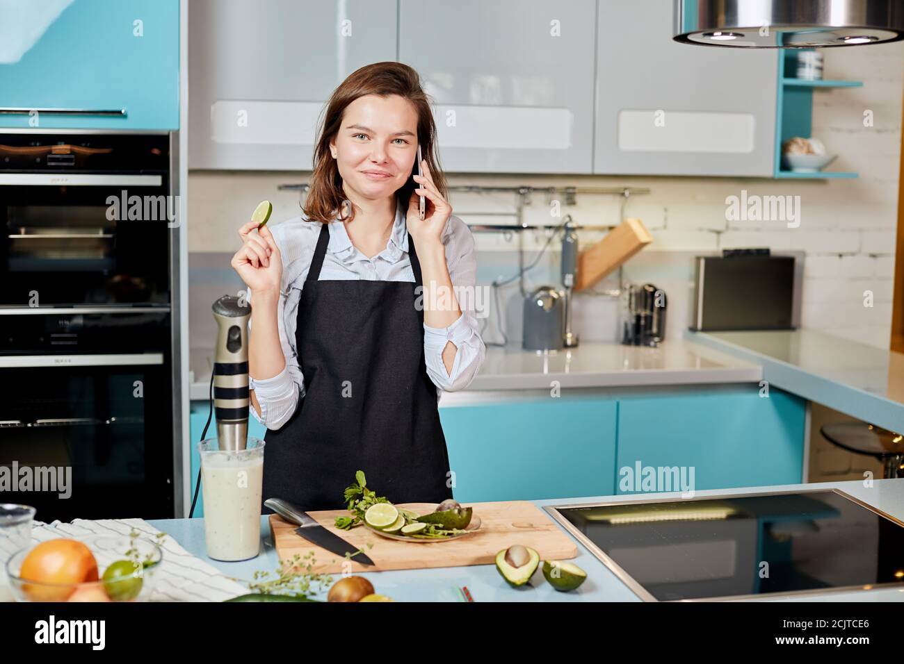 smiling pleasant girl is talking with her best friend while cooking in ...
