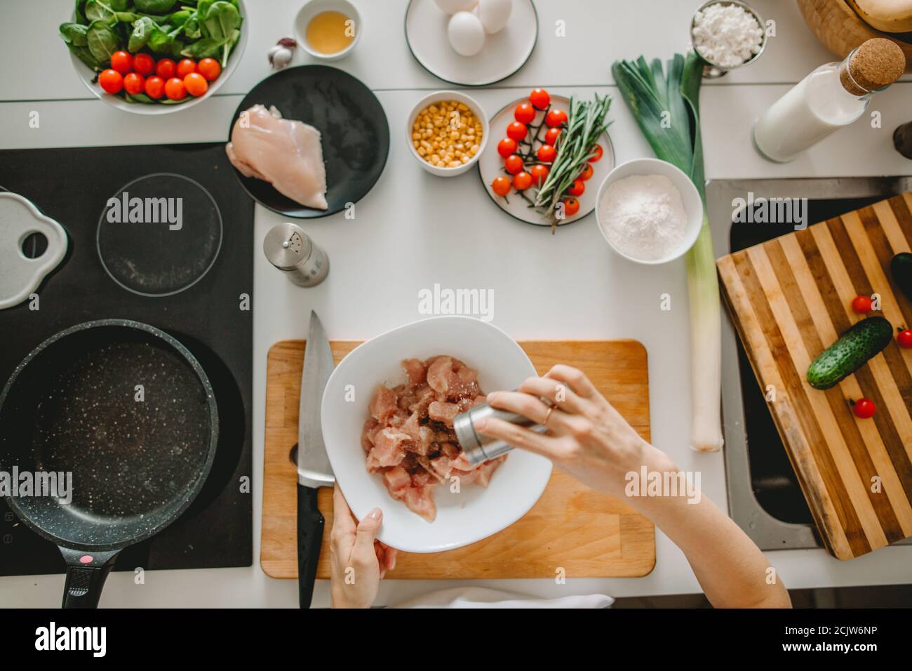 female cook salting meat on the plate. top view.sprinkle salt on meat ...