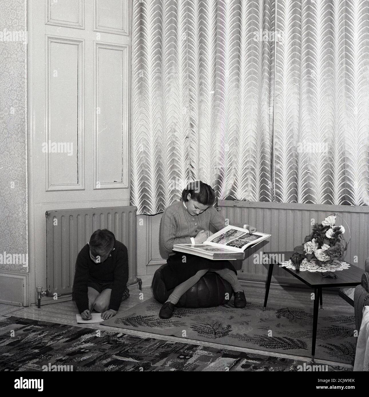 1960s, historical, young girl and boy sitting by the radiators in a ...